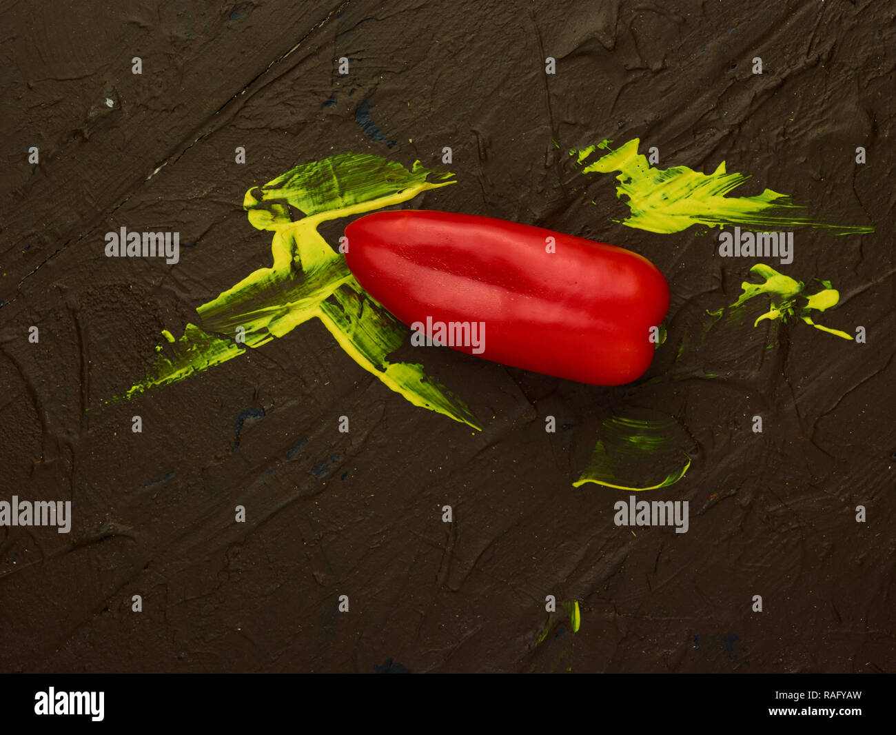 Single red mini sweet pepper against dark background with yellow flecks ...