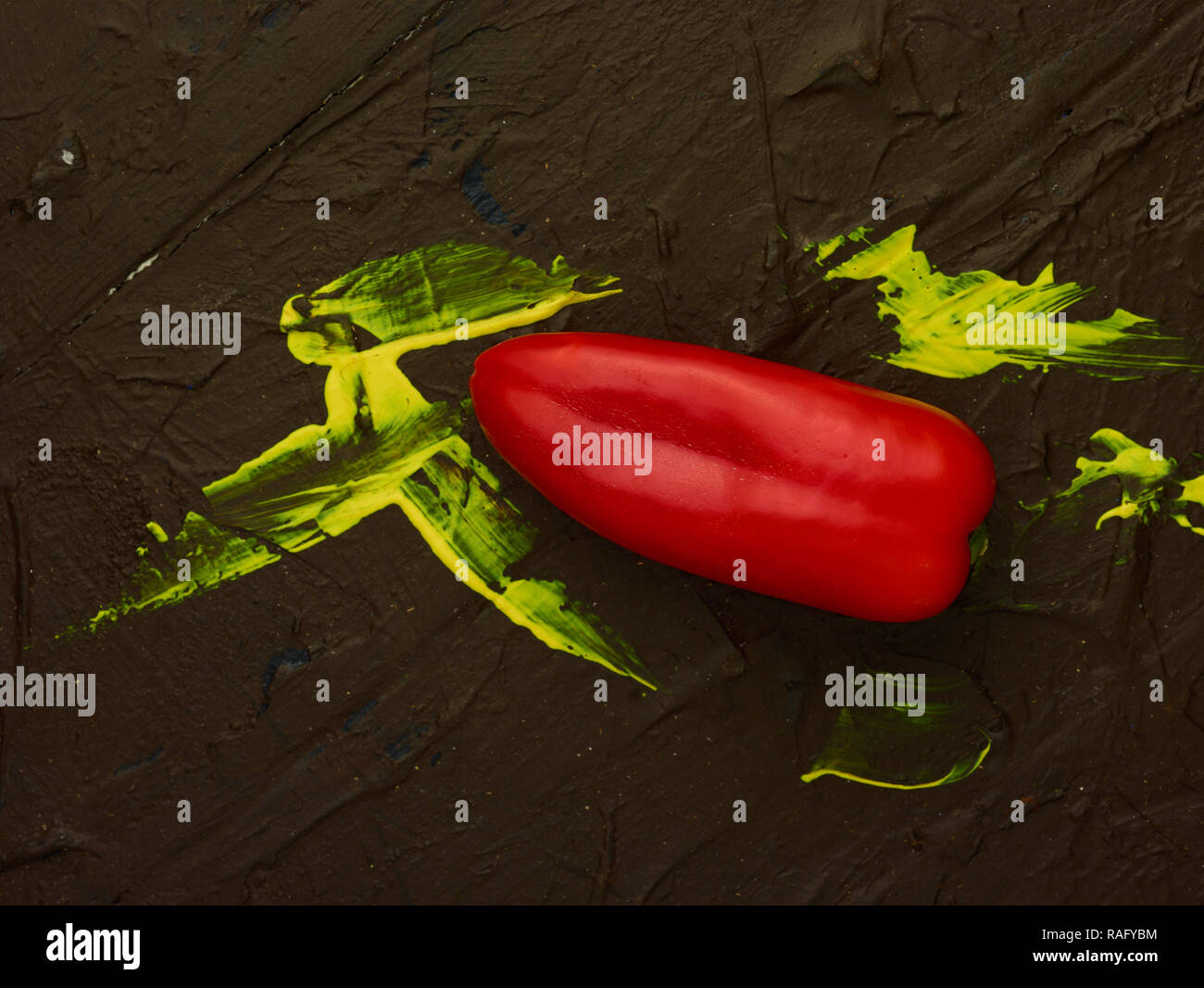 Single red mini sweet pepper against dark background with yellow flecks ...
