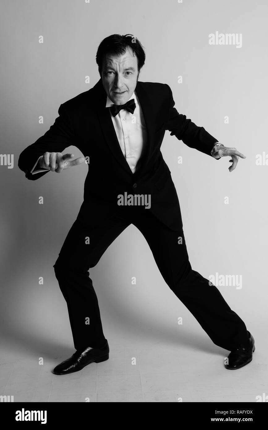 Full body shot of mature handsome businessman as secret agent in black ...