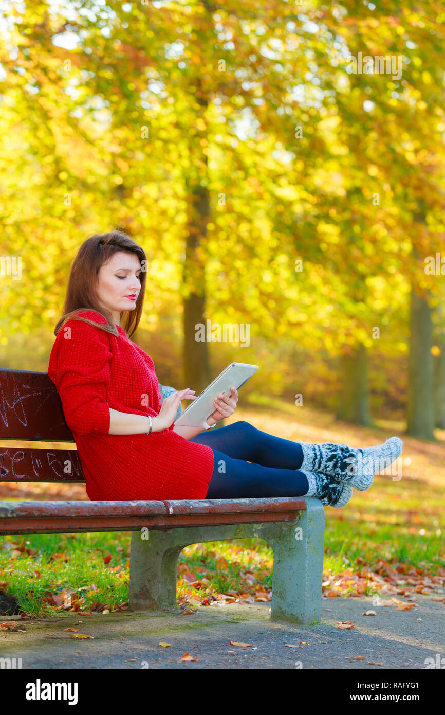 Outdoor technology nature autumn concept. Lady browsing tablet in ...