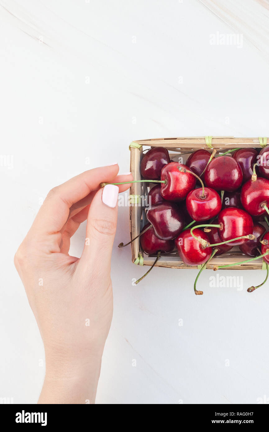 Creative top view of fresh ripe cherry in a small wicker basket with ...
