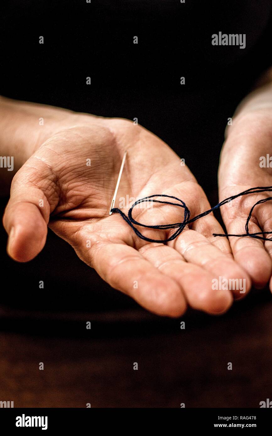 Old women holding her thread and the needle in her hands Stock Photo ...