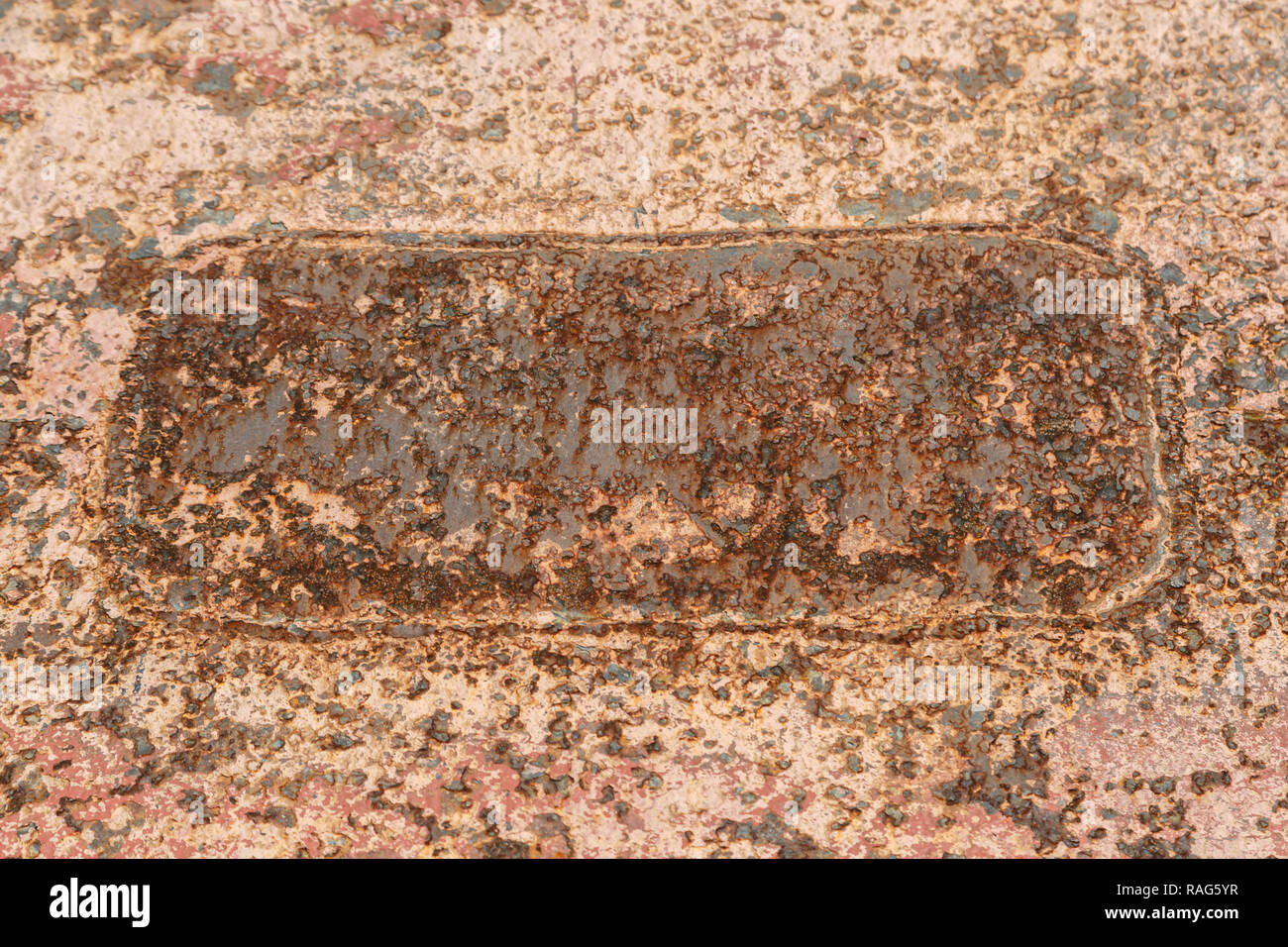 Rusty thick metal surface with paint residue and a rectangular welded ...