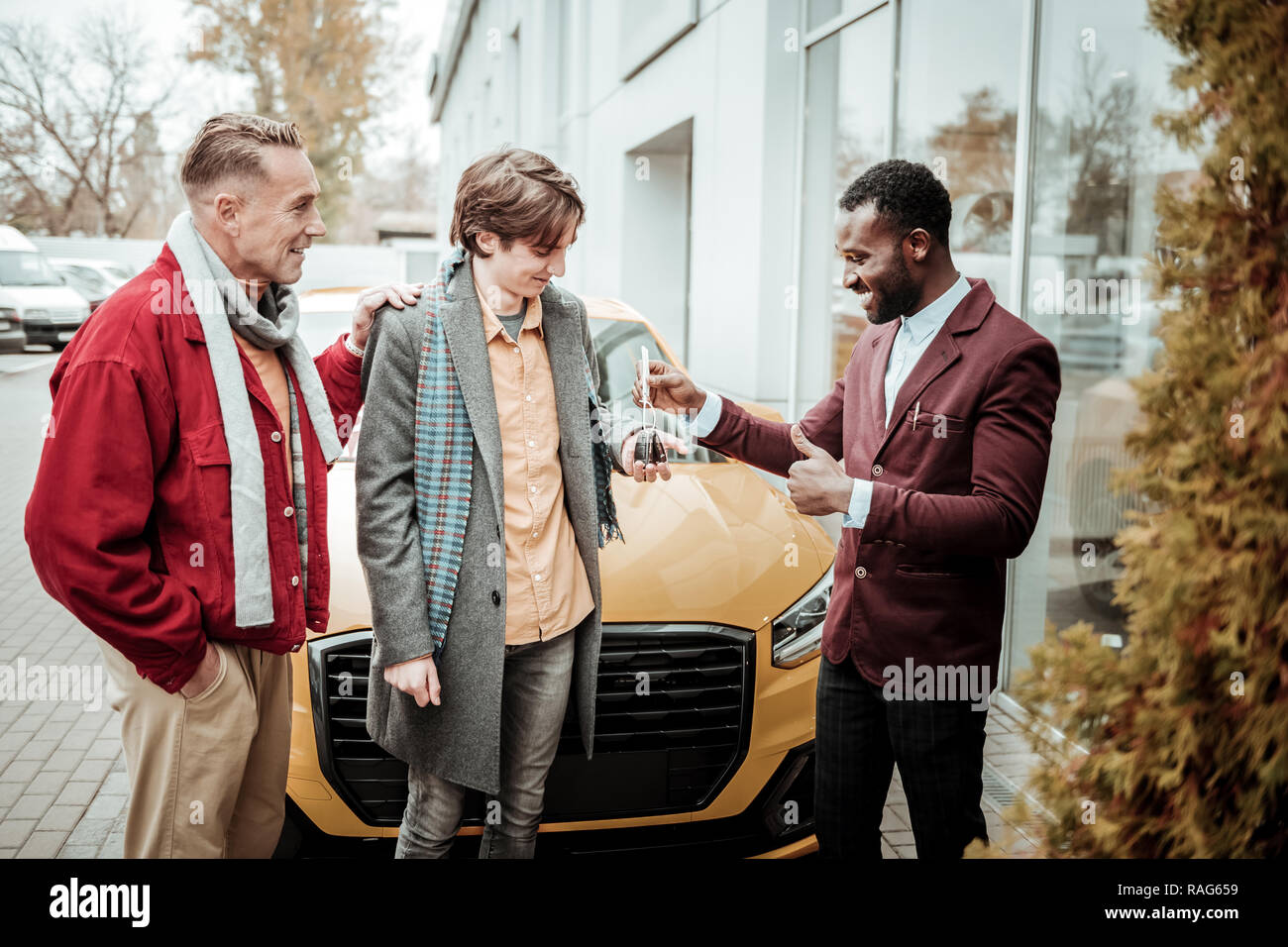 Sales manager giving car keys to young son after father bought him car ...