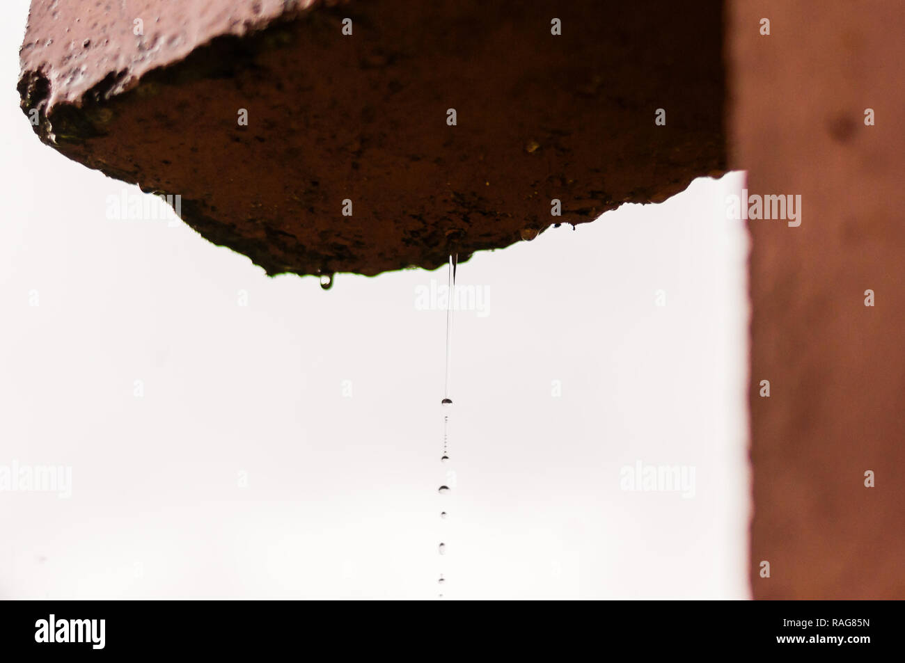 Raindrops falling down in a rows from concrete construction frame ...