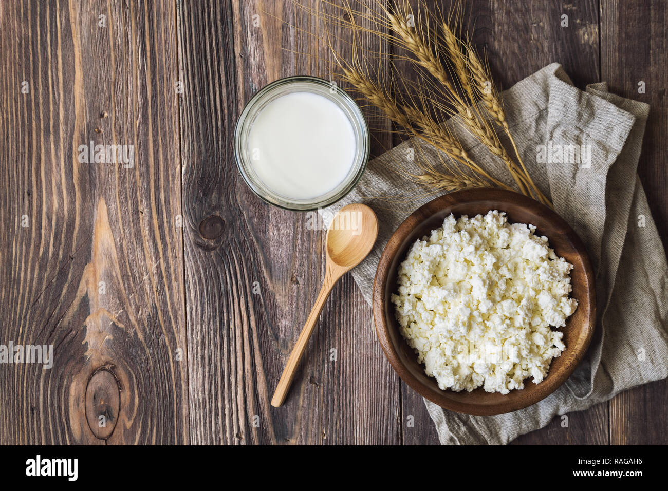 Cottage cheese, milk and ears of wheat on rustic wooden background ...