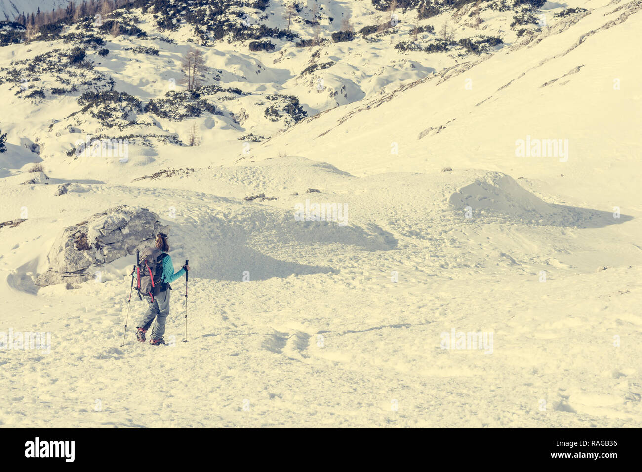 Female alpinist descending into mountain valley crossing flakes of snow ...