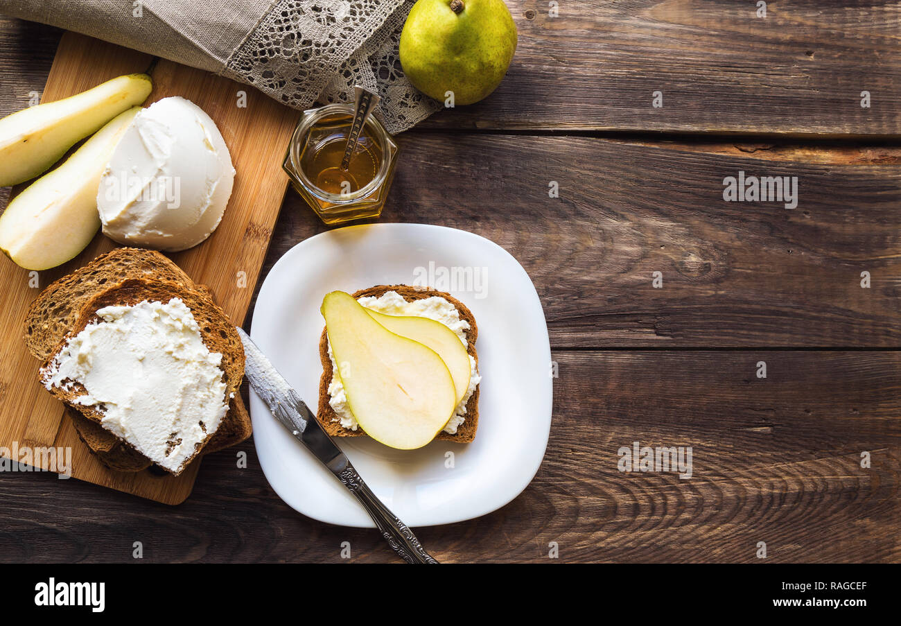 Toast with pear, ricotta cheese and honey on rustic wooden background ...