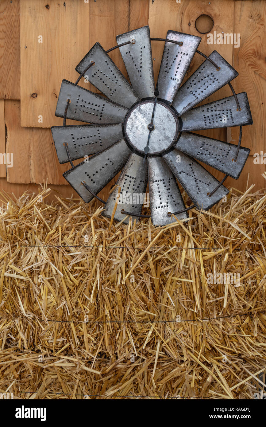 roman numeral tin clock sitting on a bale of hay against an unfinished ...