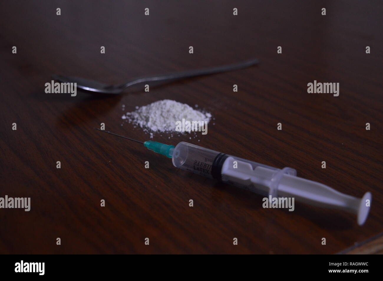 Narcotics being prepared. Needles, spoon and white powder on a table ...