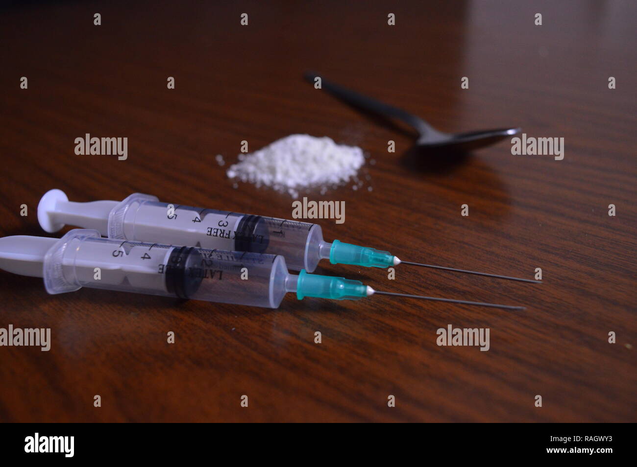 Narcotics being prepared. Needles, spoon and white powder on a table ...