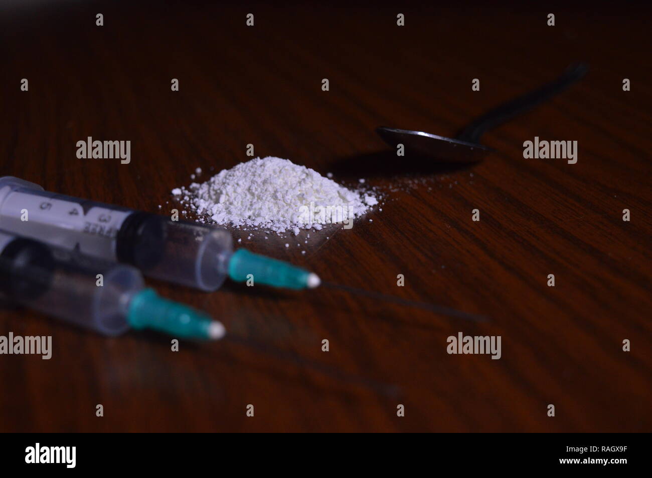 Narcotics being prepared. Needles, spoon and white powder on a table ...