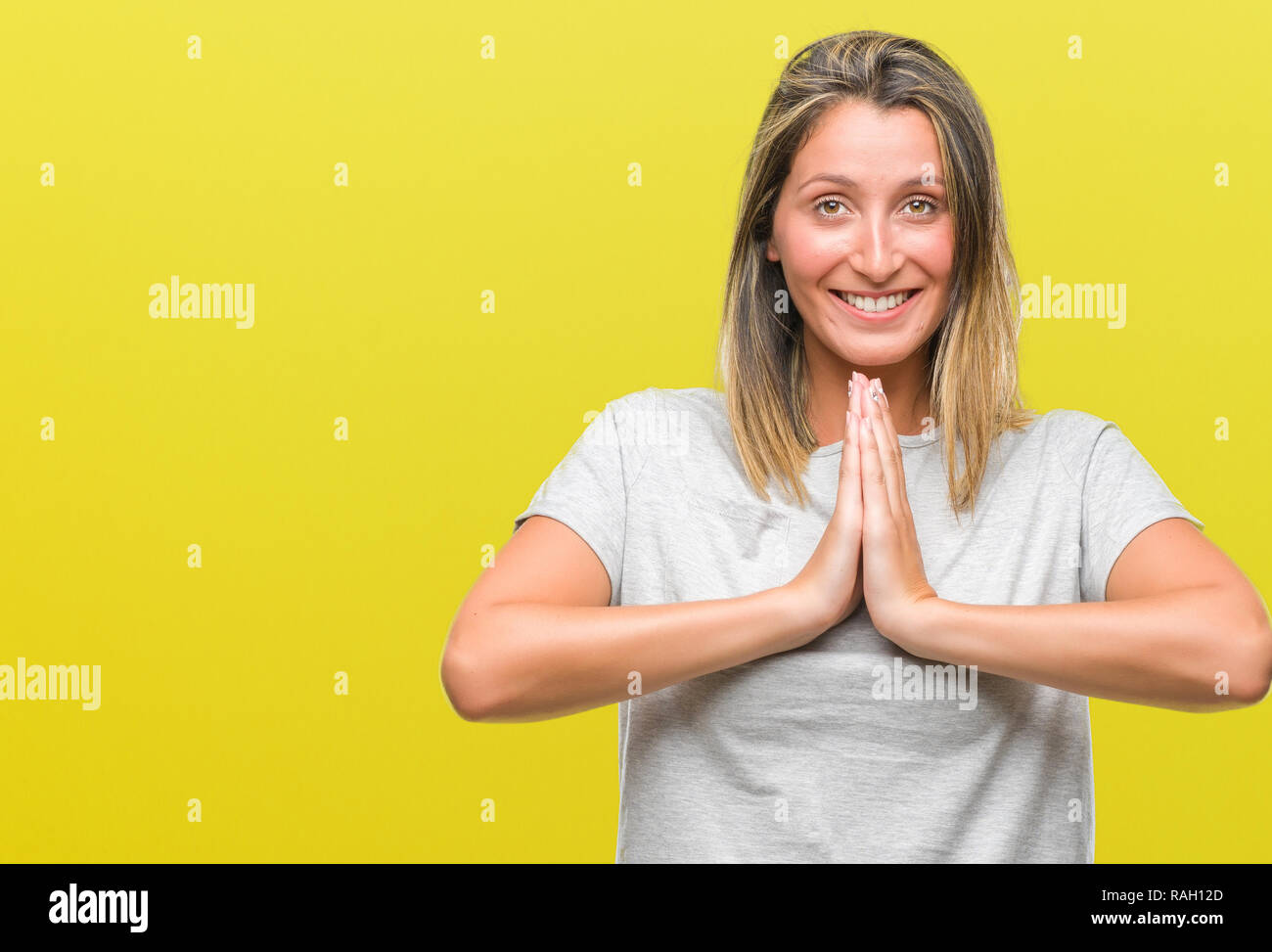 Young beautiful woman over isolated background praying with hands ...