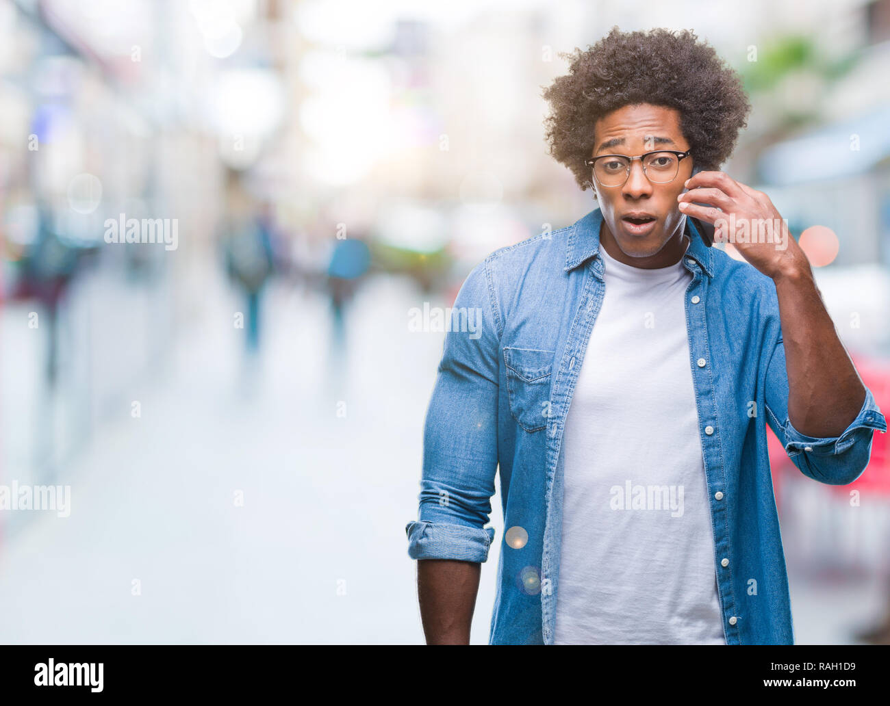 Afro american man talking on the phone over isolated background scared ...