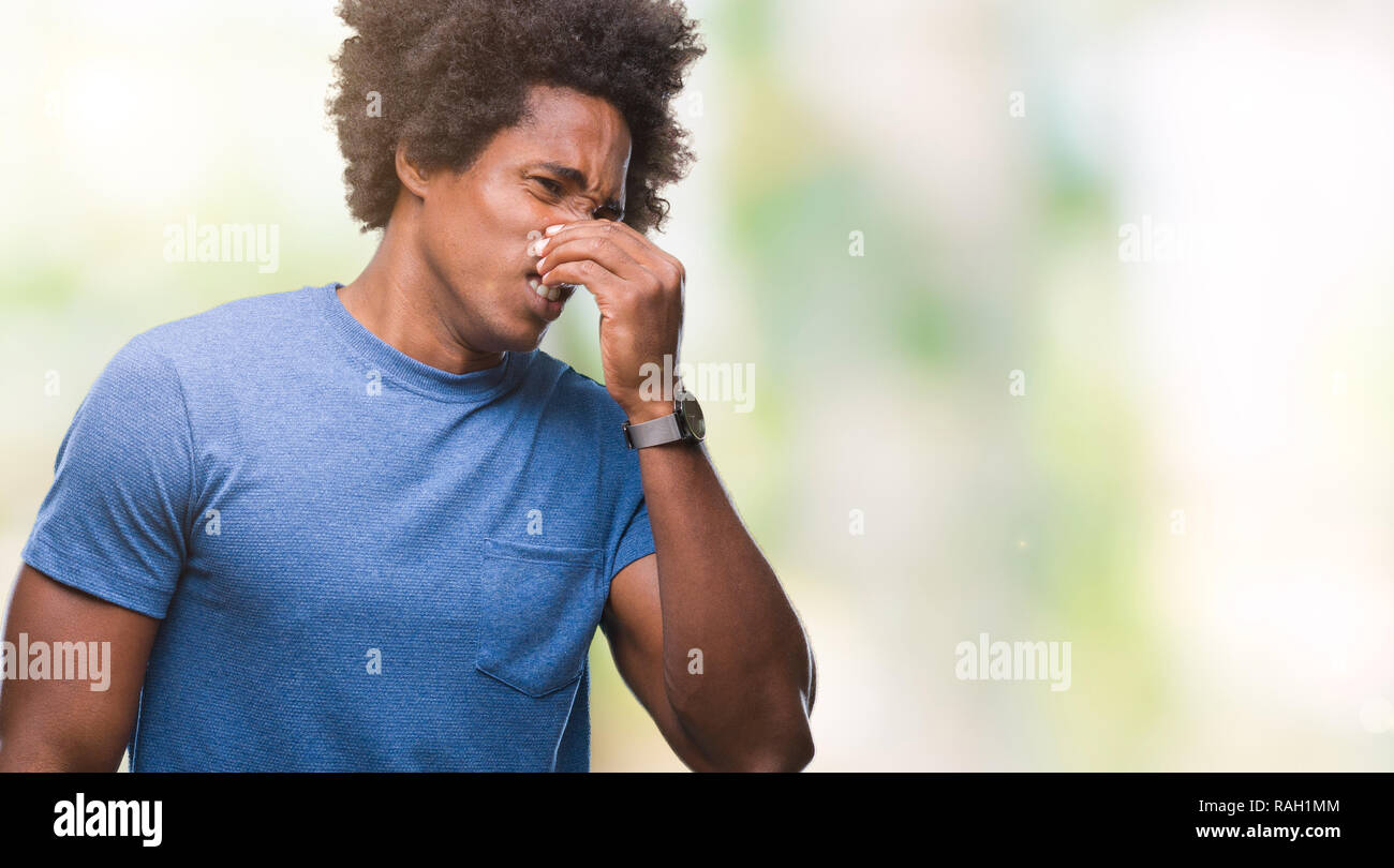 Afro american man over isolated background smelling something stinky ...