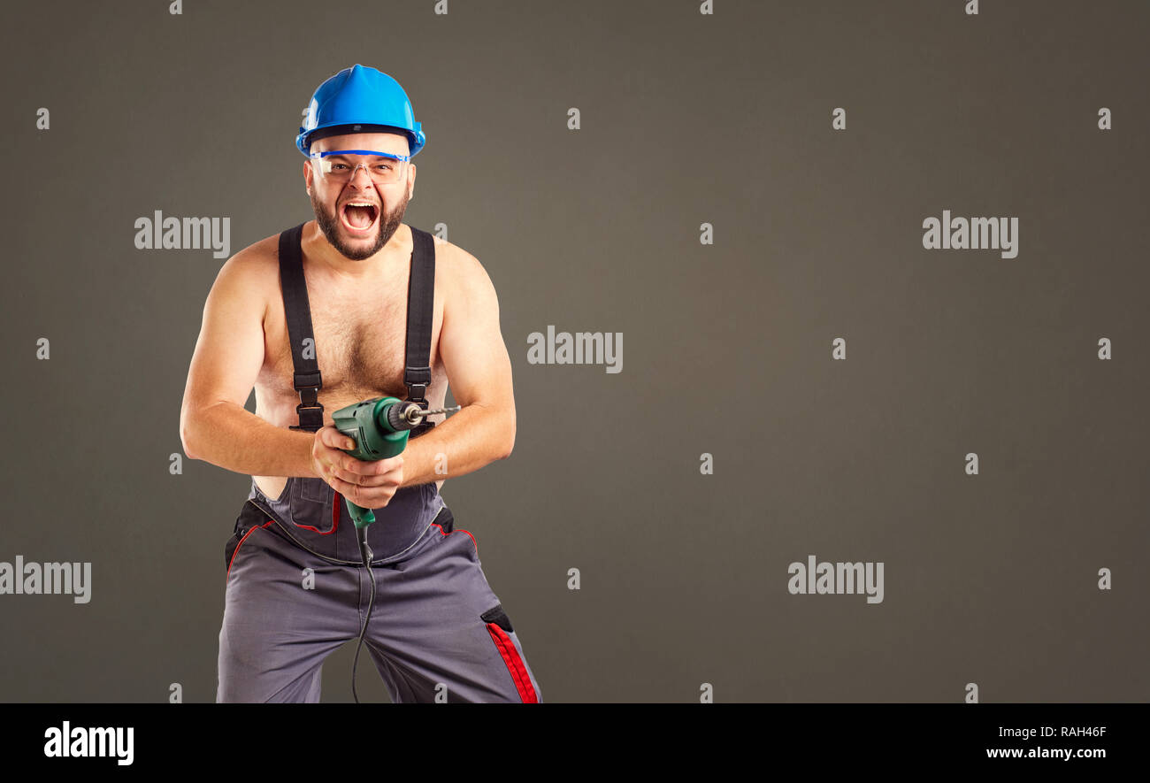 Funny builder with a drill in his hands Stock Photo - Alamy