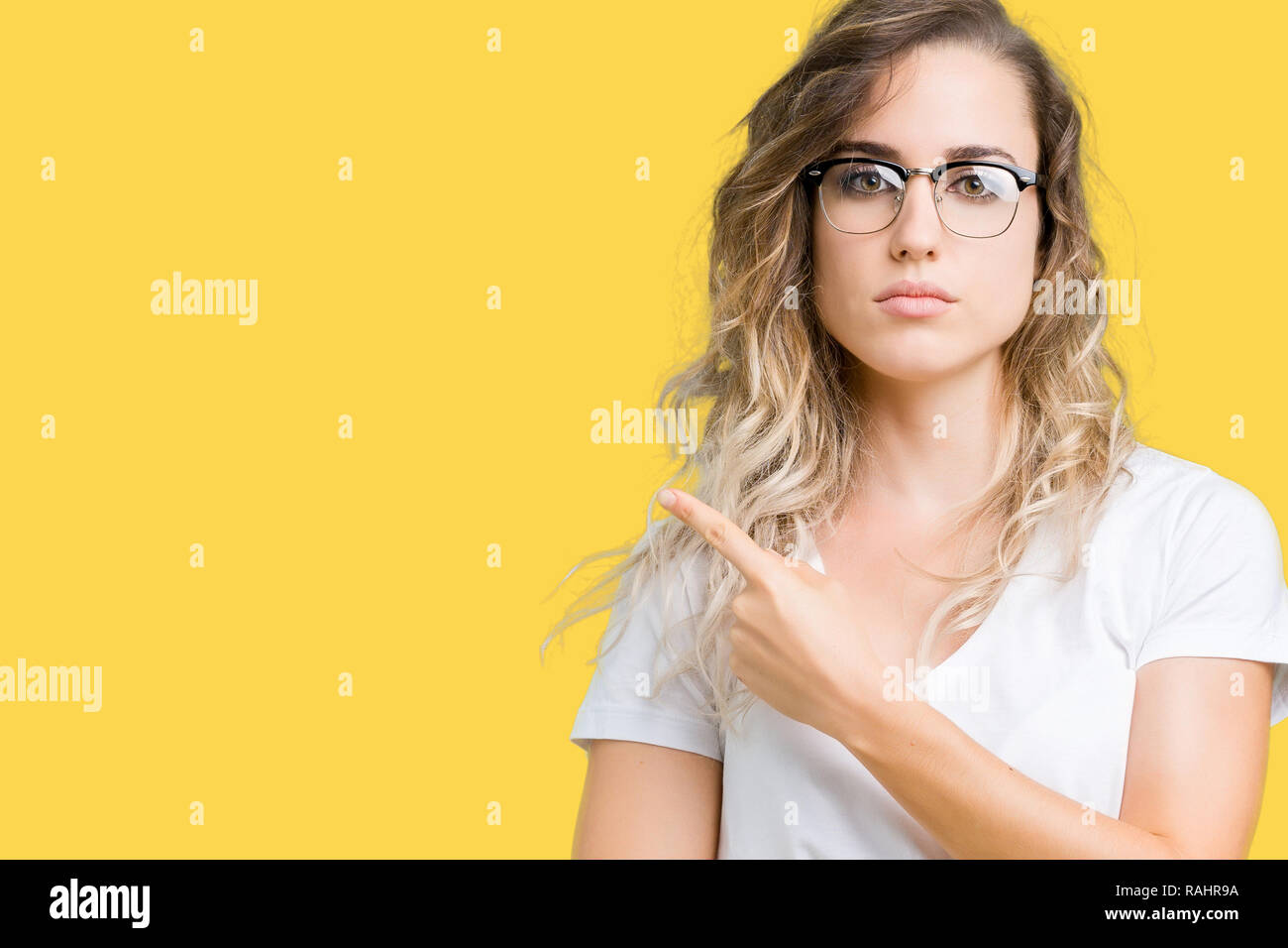 Beautiful young blonde woman wearing glasses over isolated background ...