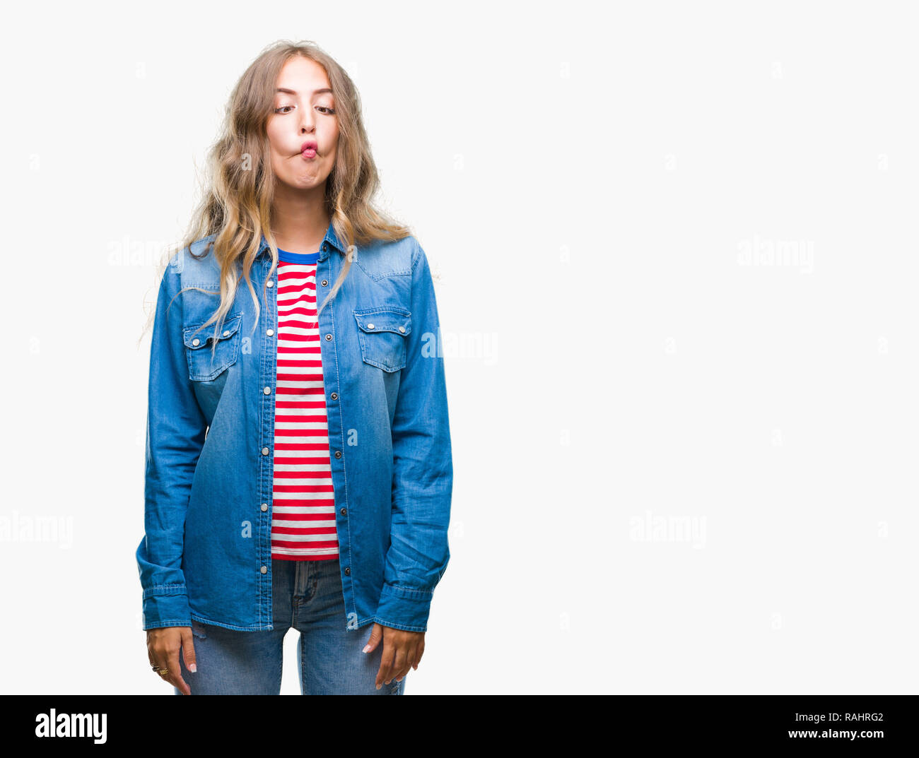 Beautiful young blonde woman over isolated background making fish face ...