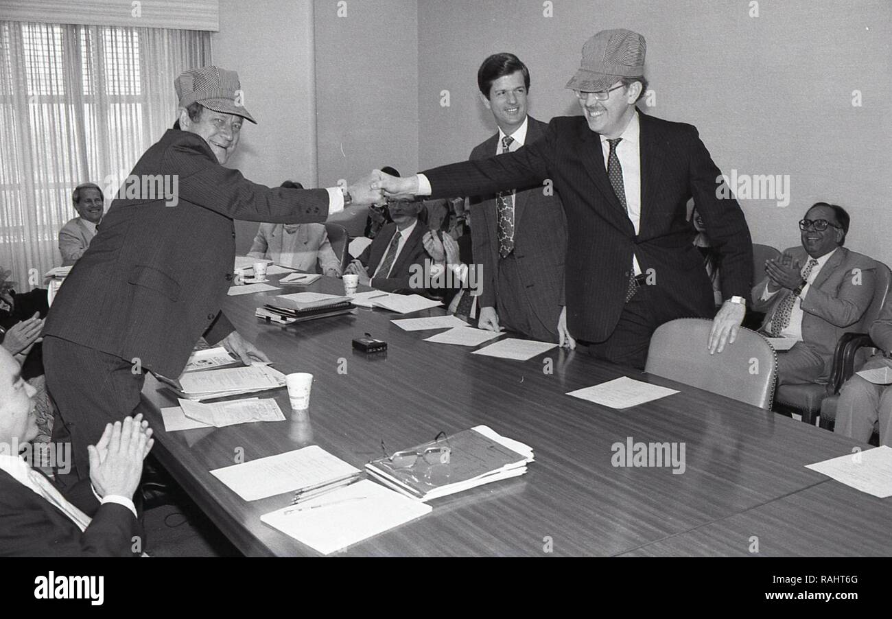 TWO MEN GREETING EACH OTHER ACROSS THE TABLE WITH OTHER MEN AND WOMEN ...