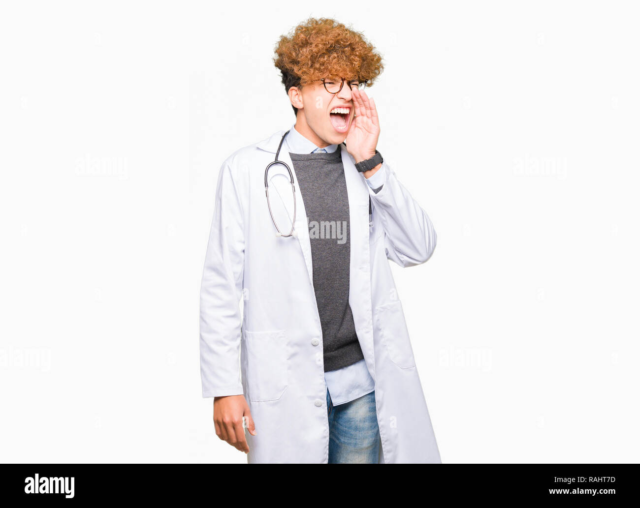 Young handsome doctor man wearing medical coat shouting and screaming ...
