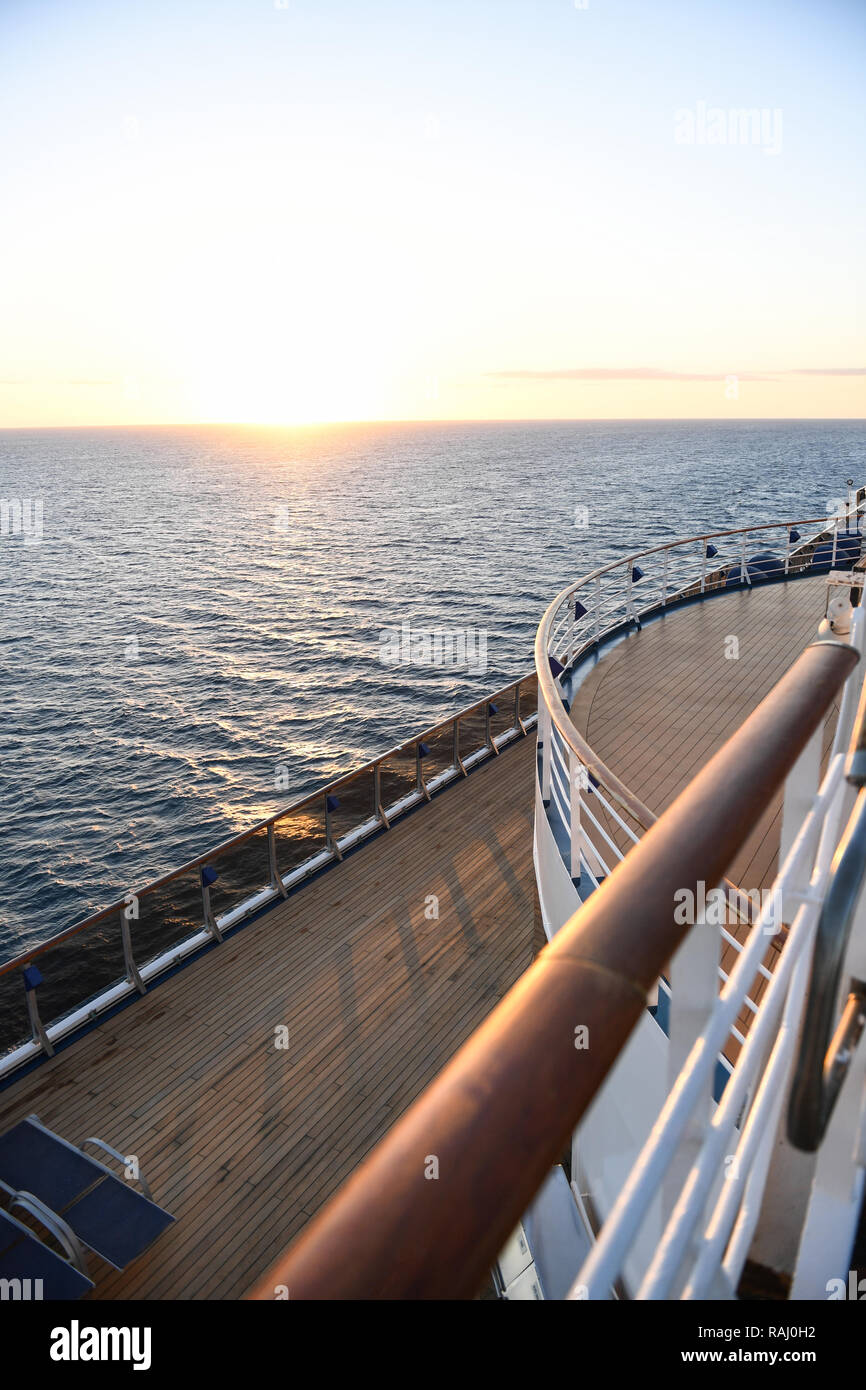 Railing and deck flooring of a cruise ship at sunset with the ocean in ...