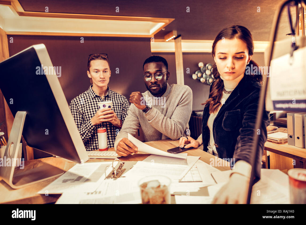 Attentive young people working together at project Stock Photo - Alamy