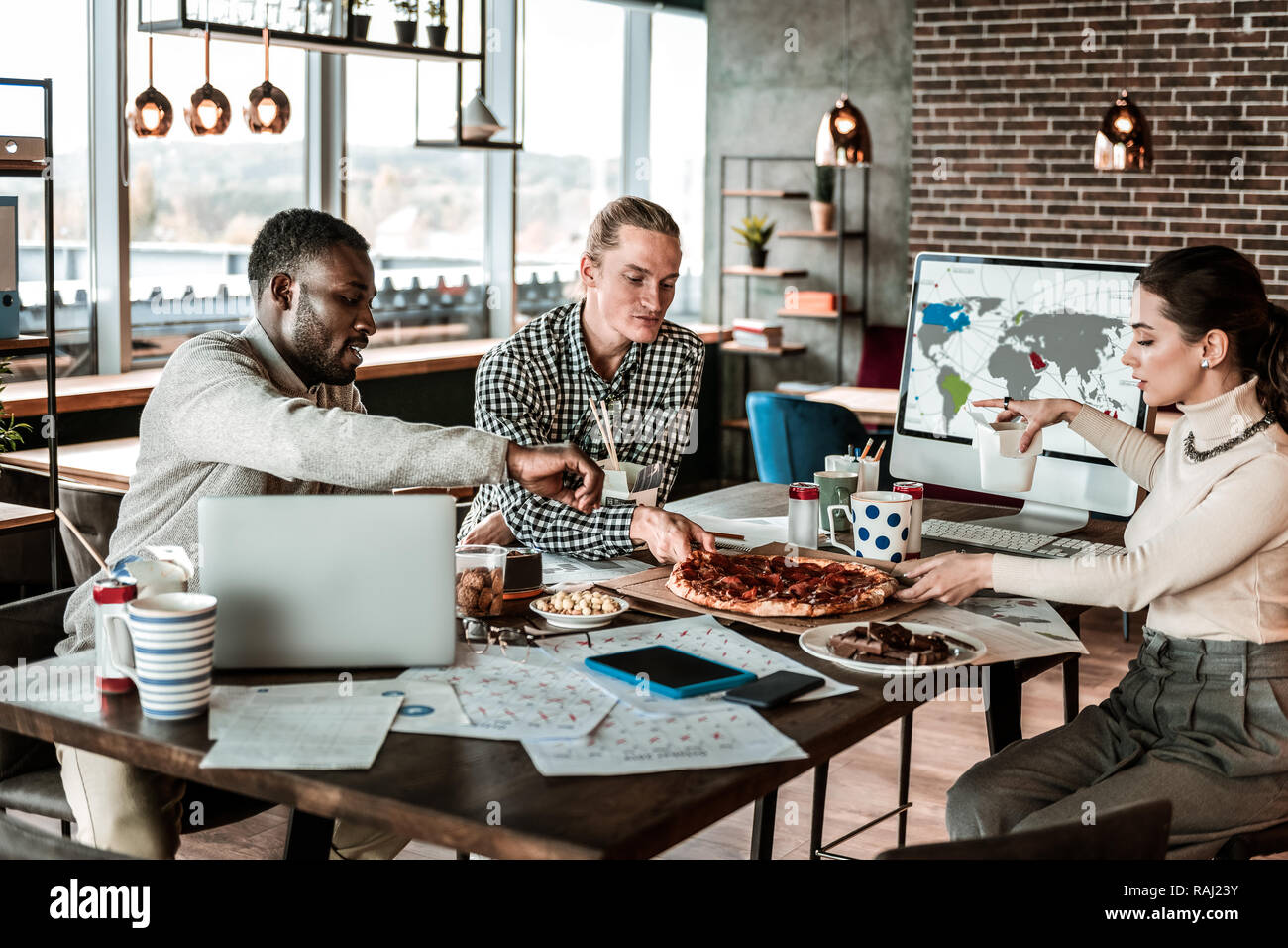 Positive delighted young people having dinner at work Stock Photo - Alamy