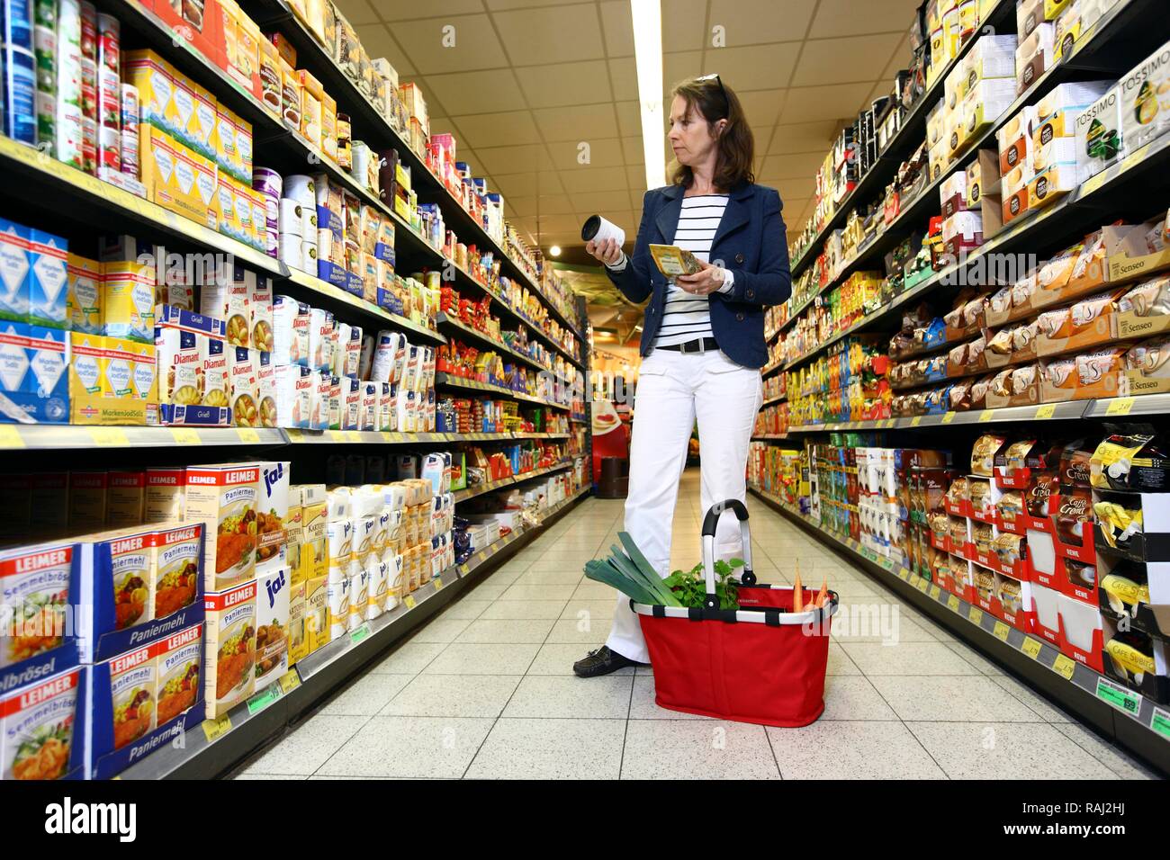 Woman purchasing flour and baking ingredients in a self-service grocery ...