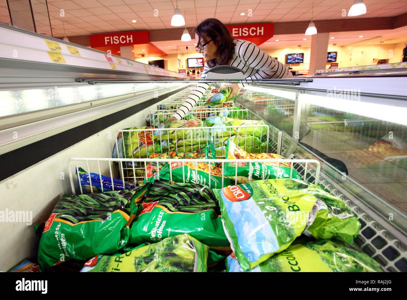 Woman purchasing frozen vegetables in the frozen food section of a self ...