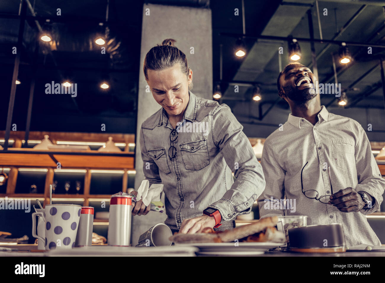 Pleased young man cleaning table after dinner Stock Photo - Alamy