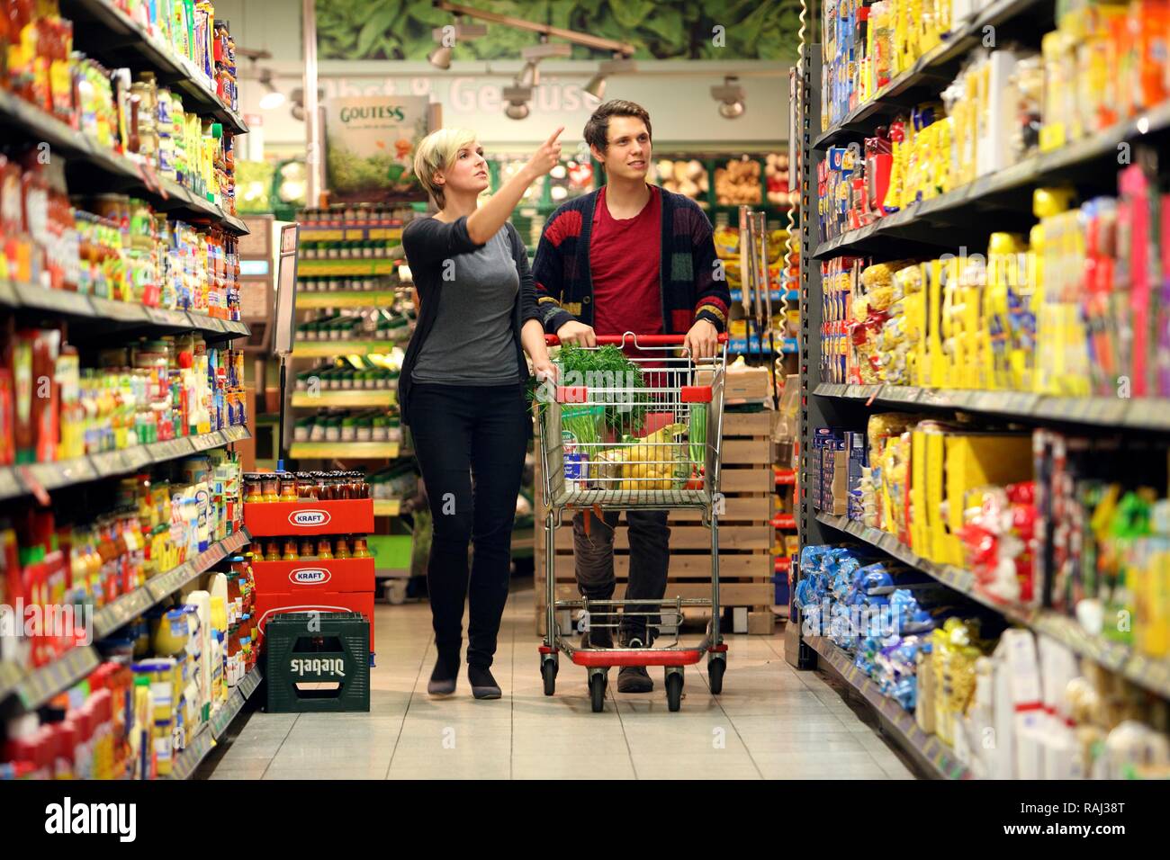Young couple grocery shopping at the supermarket, shelves with various ...