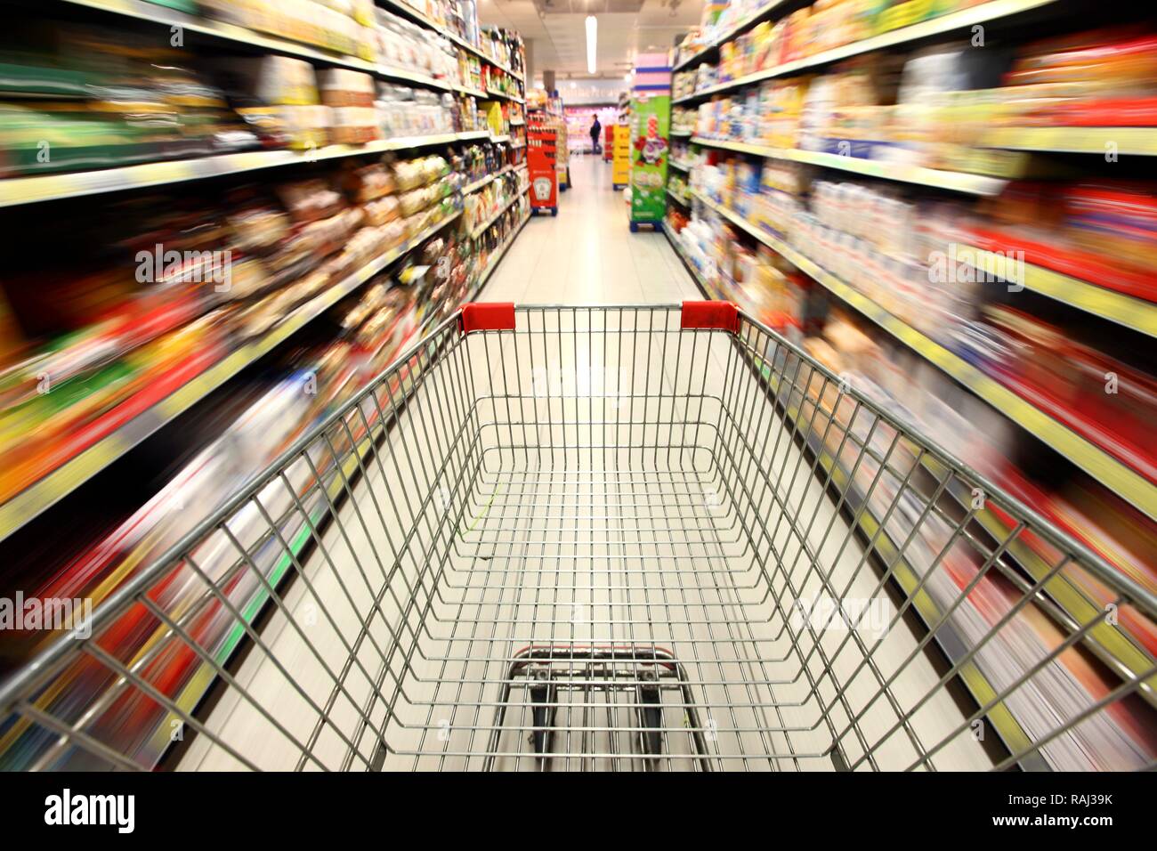 Empty shopping trolley being pushed through a corridor, food section ...
