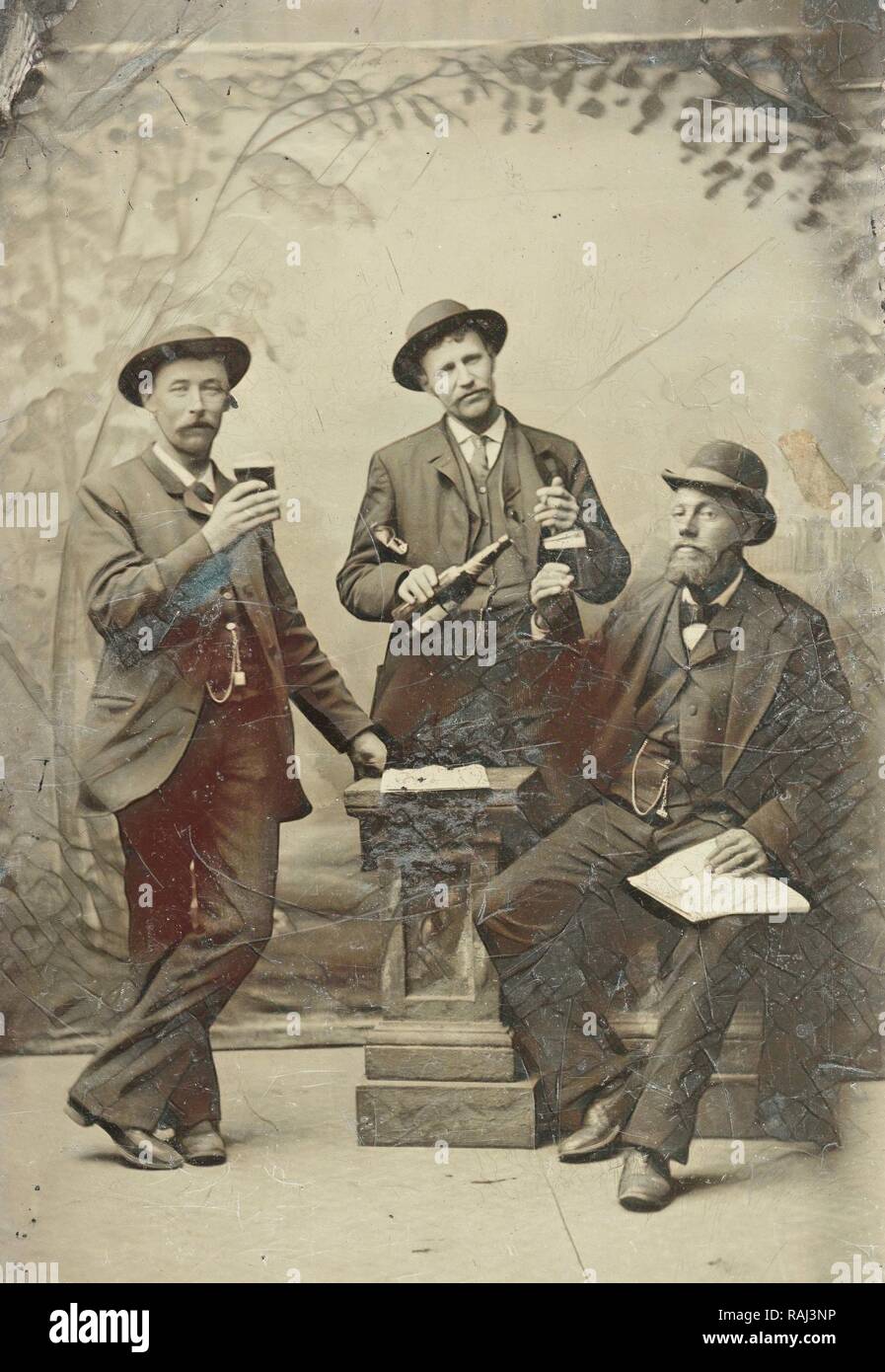 Portrait of three men with bottle and glasses, standing and sitting in ...