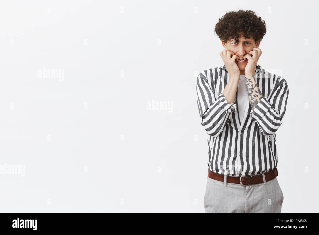 Portrait of frightened male coward with curly hair tattoos and ...