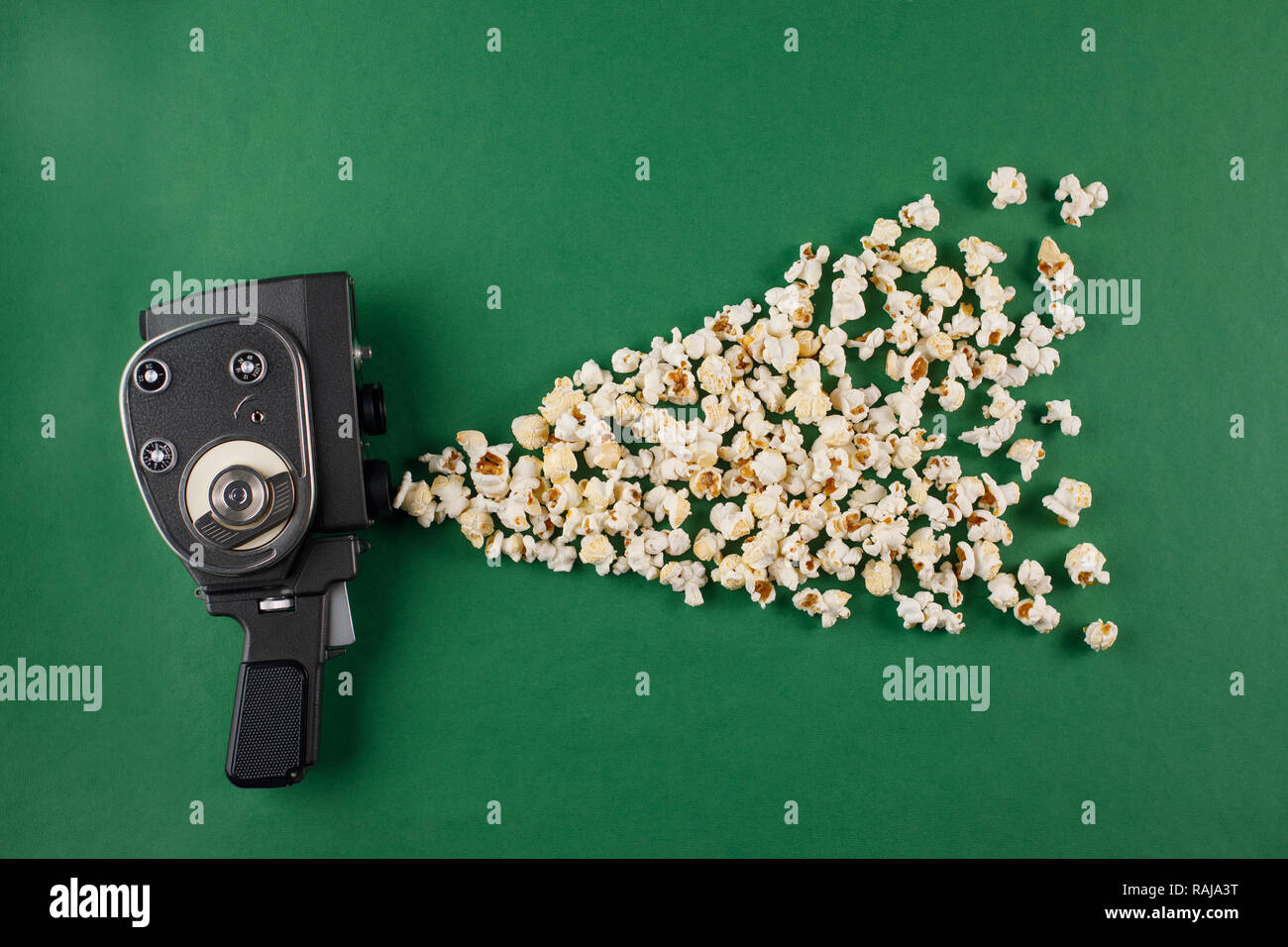 Retro movie camera with popcorn flying out of it on a green background ...