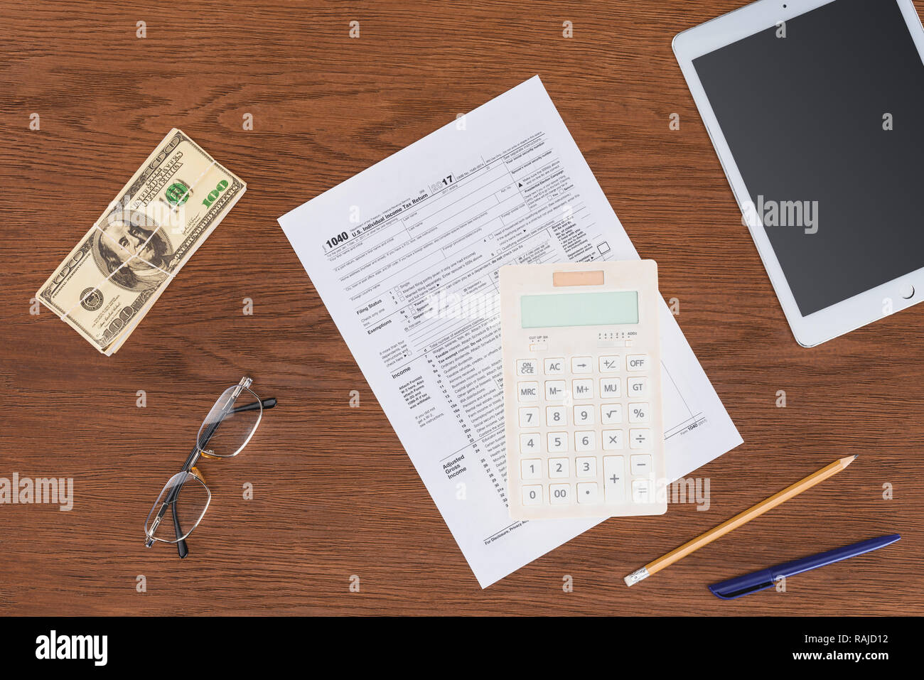 top view of tax form, calculator and dollar banknote on wooden desk at ...