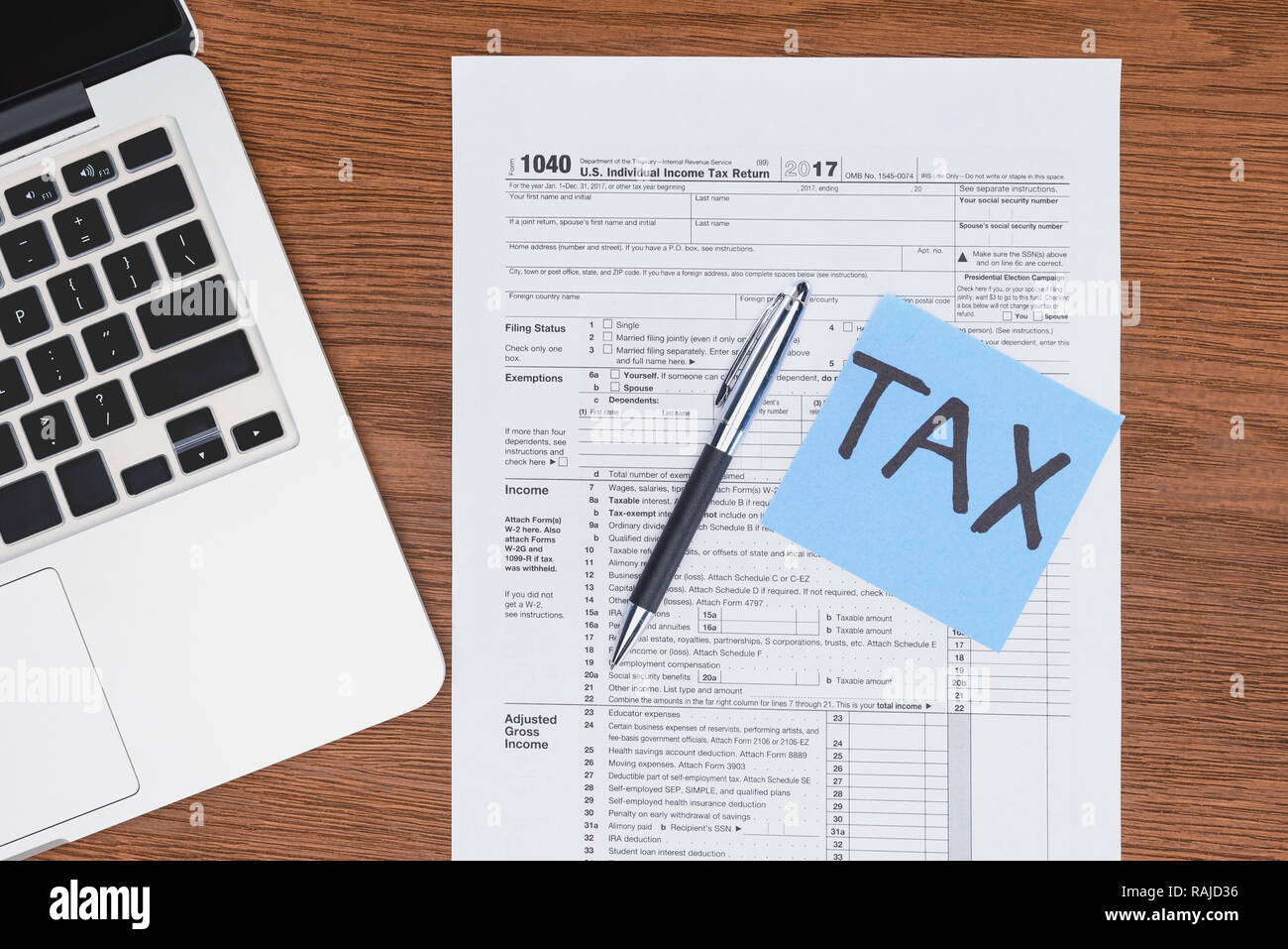 top view of tax form, laptop and blue card with 'tax' word on desk ...