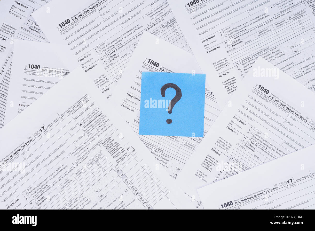 top view of question mark on blue card with tax forms on background ...