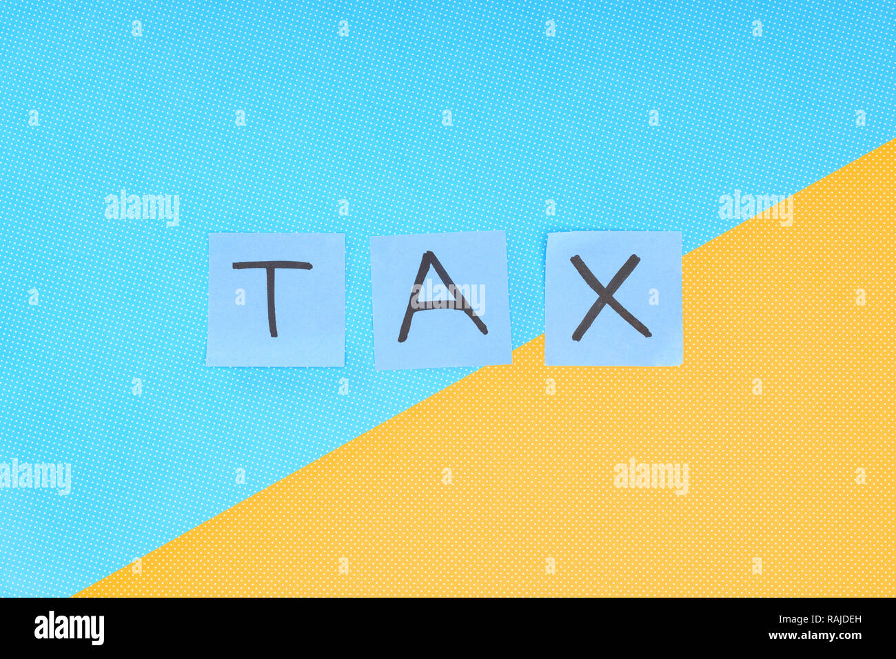 top view of word 'tax' made of blue cards on blue and yellow background ...