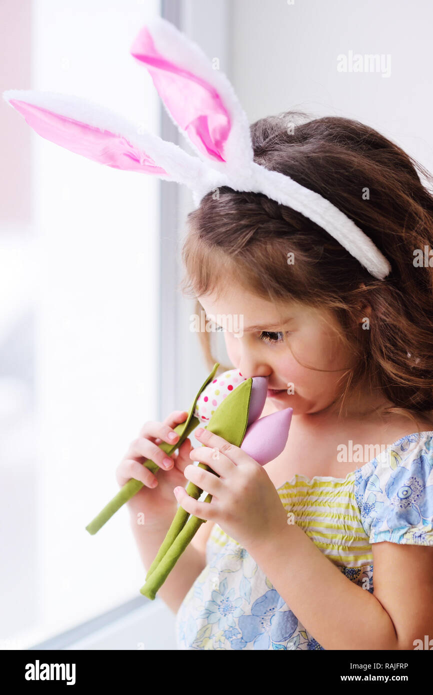 girl with rabbit ears sniffing flowers on the window background Stock ...