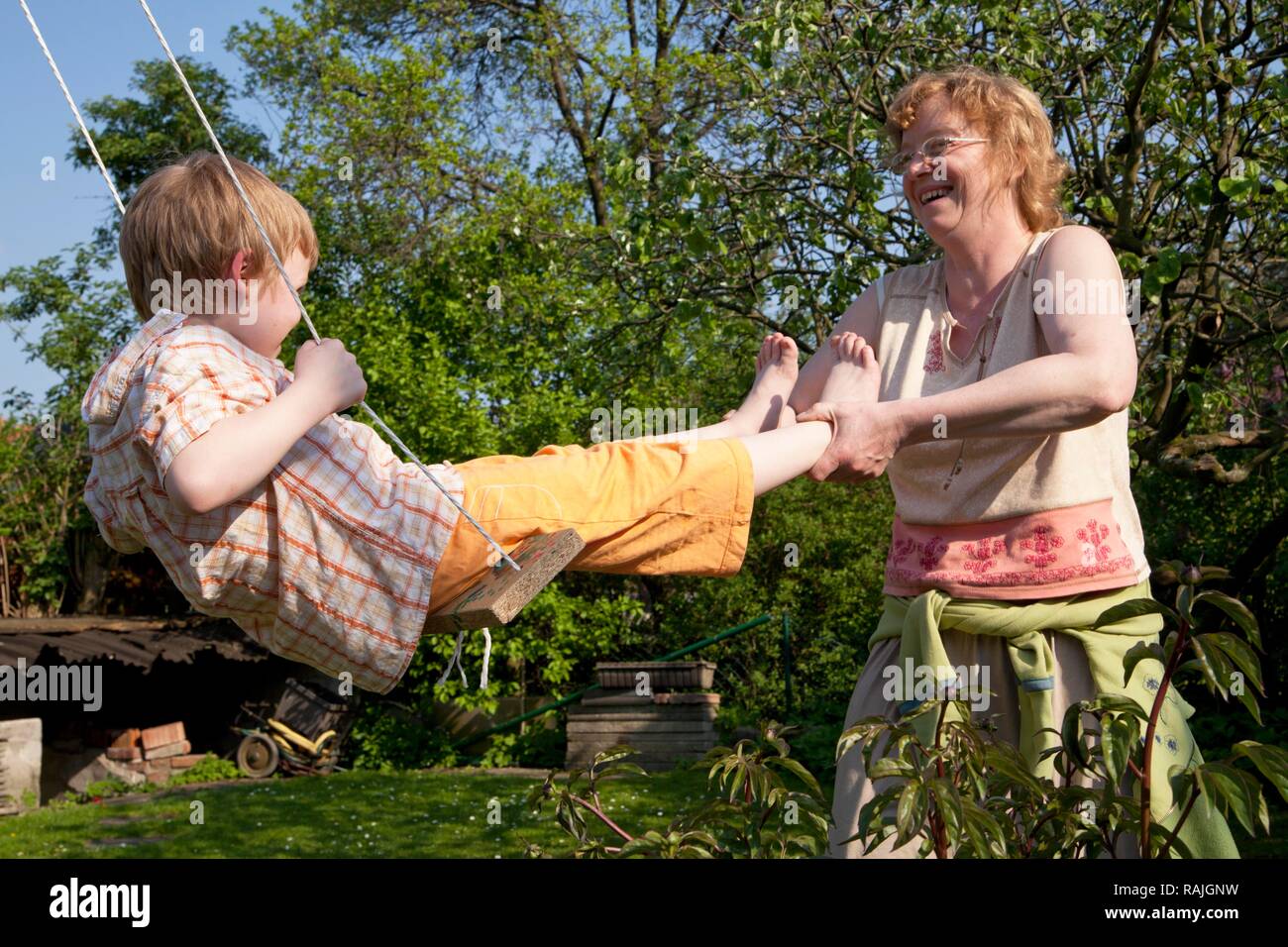 Woman pushing a little boy on a swing Stock Photo - Alamy