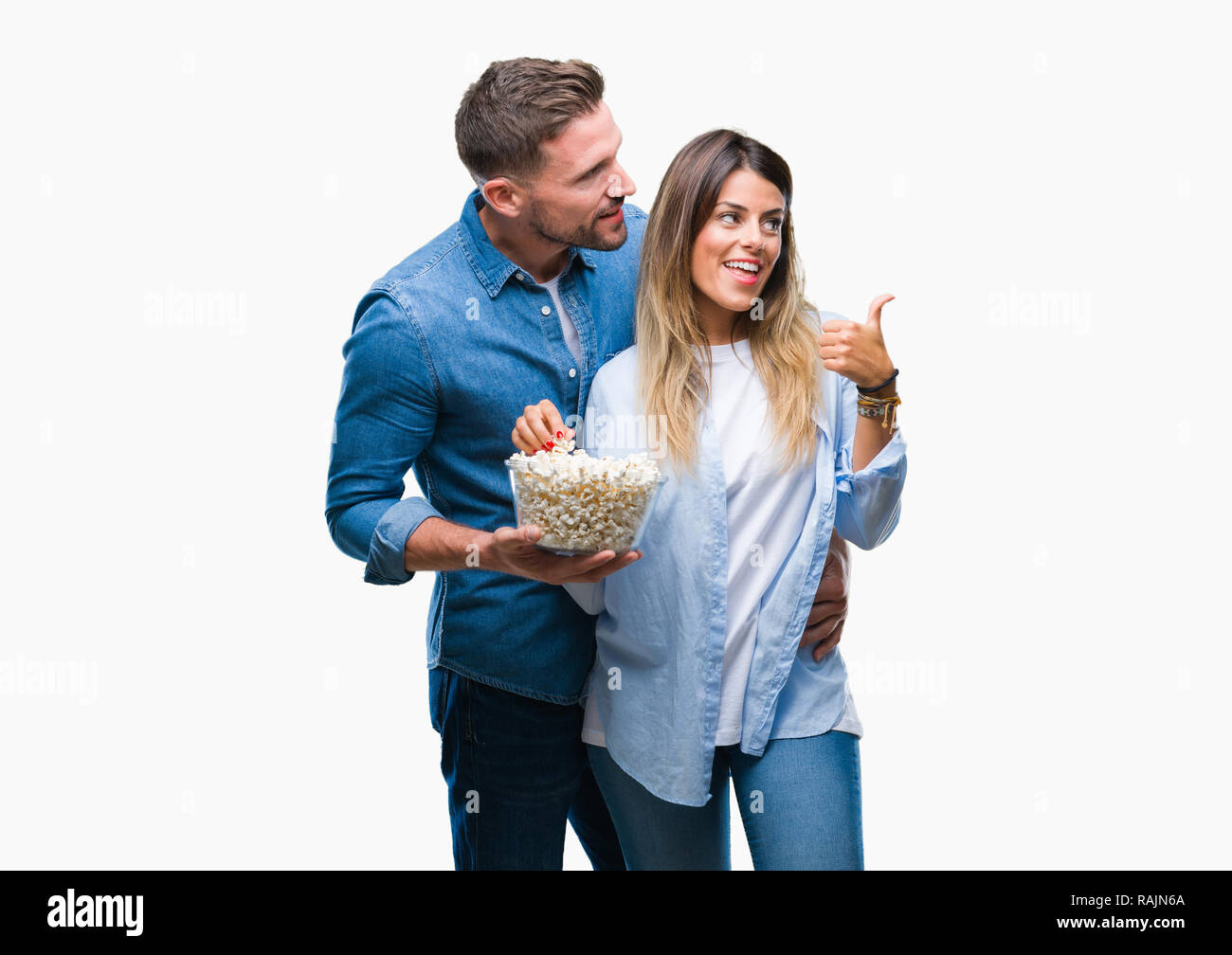 Young couple in love eating popcorn over isolated background pointing ...