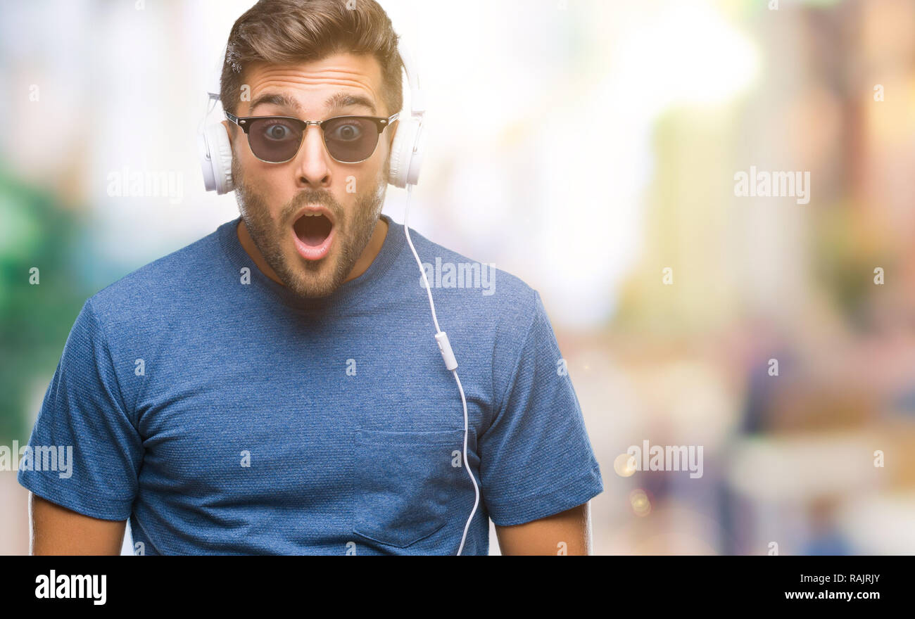 Young handsome man wearing headphones listening to music over isolated ...