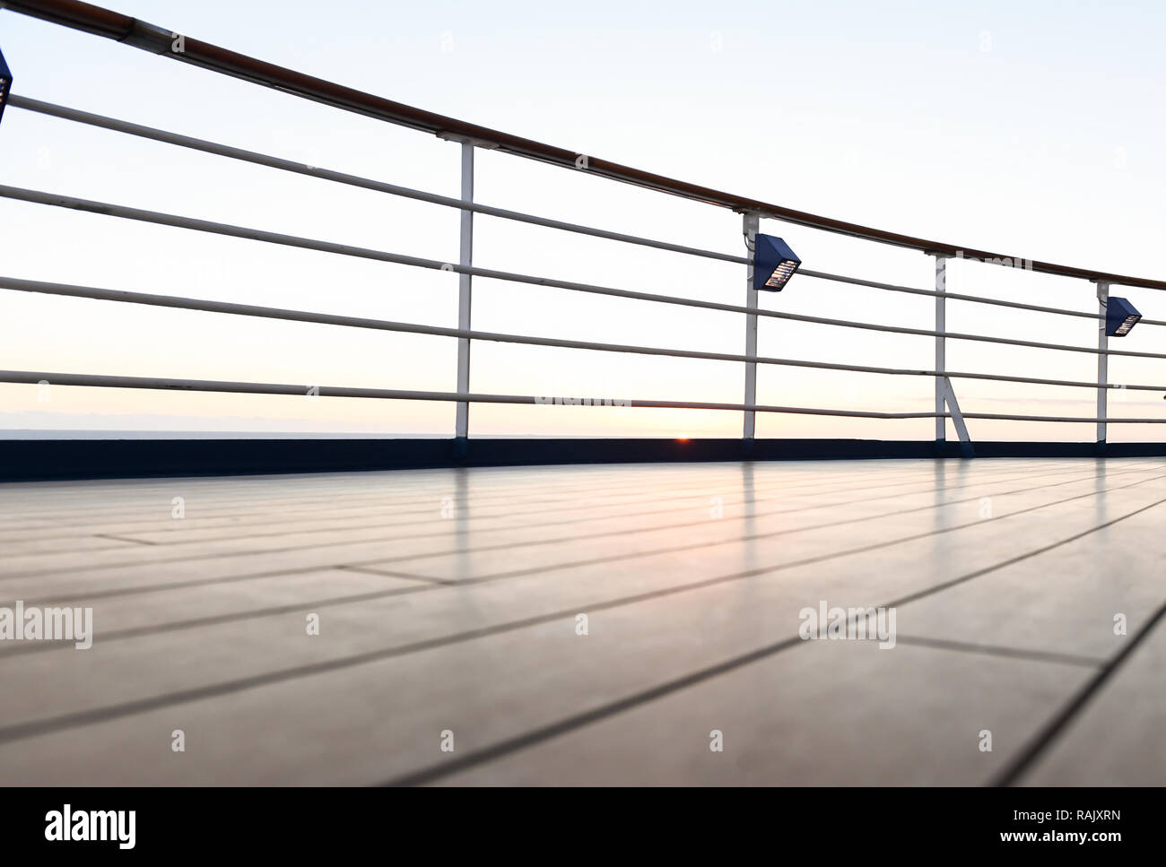 Railing and deck flooring of a cruise ship at sunset with the ocean in ...