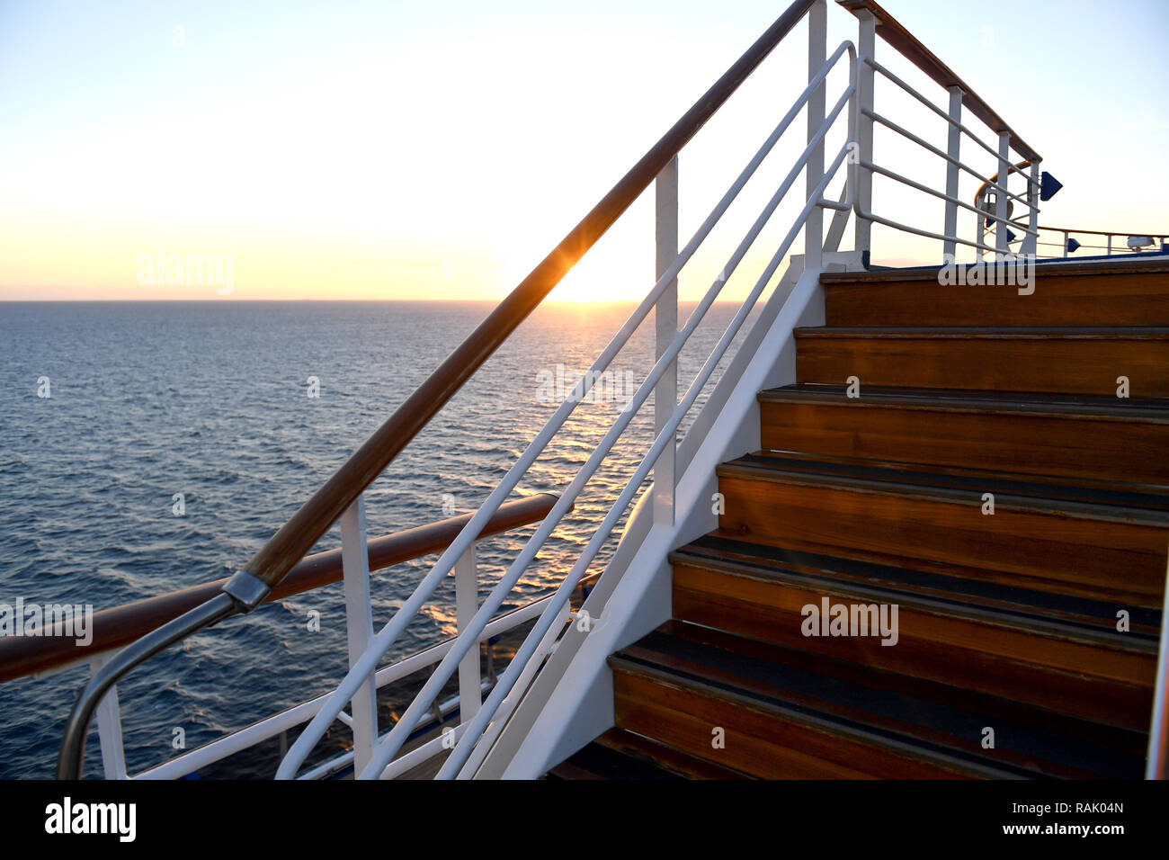 Railing and deck flooring of a cruise ship at sunset with the ocean in ...