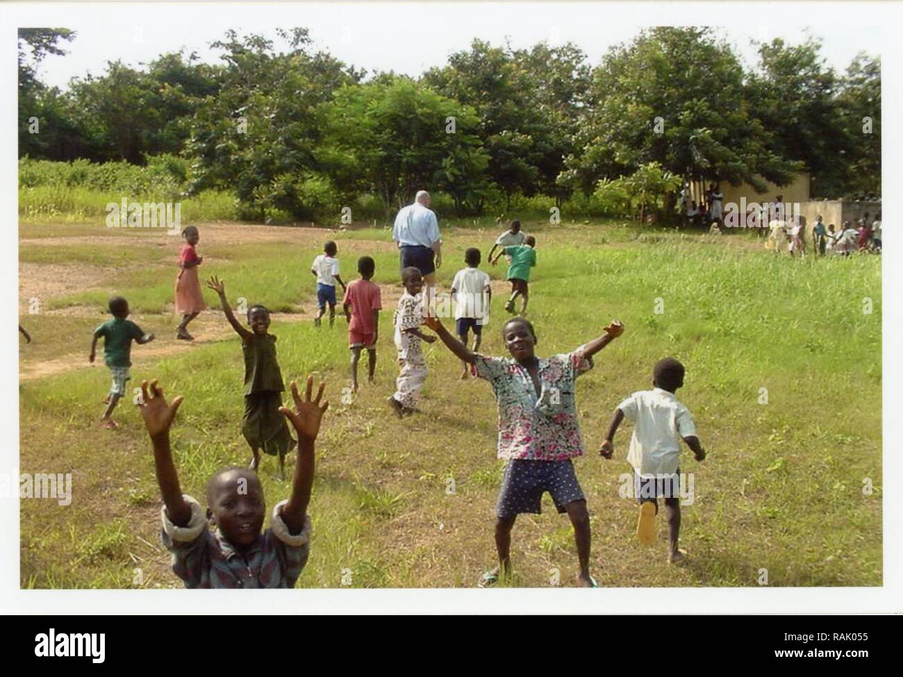 A GROUP OF KIDS PLAYING IN THE FIELDS WITH A MAN WALKING WITH THEM ...