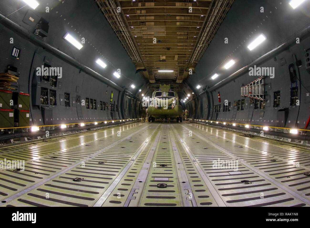 A CH-47F Chinook helicopter waits to be unloaded from the cargo bay of ...