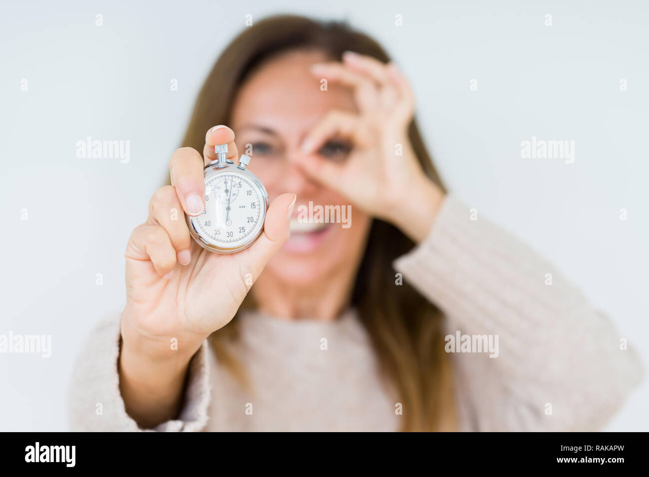 Middle age woman holding stopwatch isolated background with happy face ...