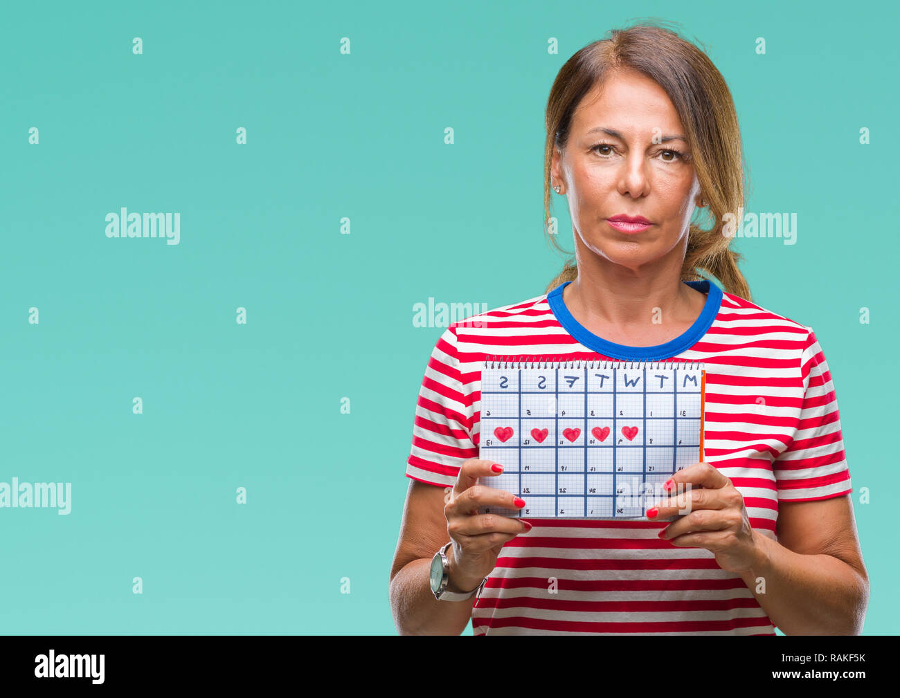 Middle age senior hispanic woman holding menstruation calendar over ...