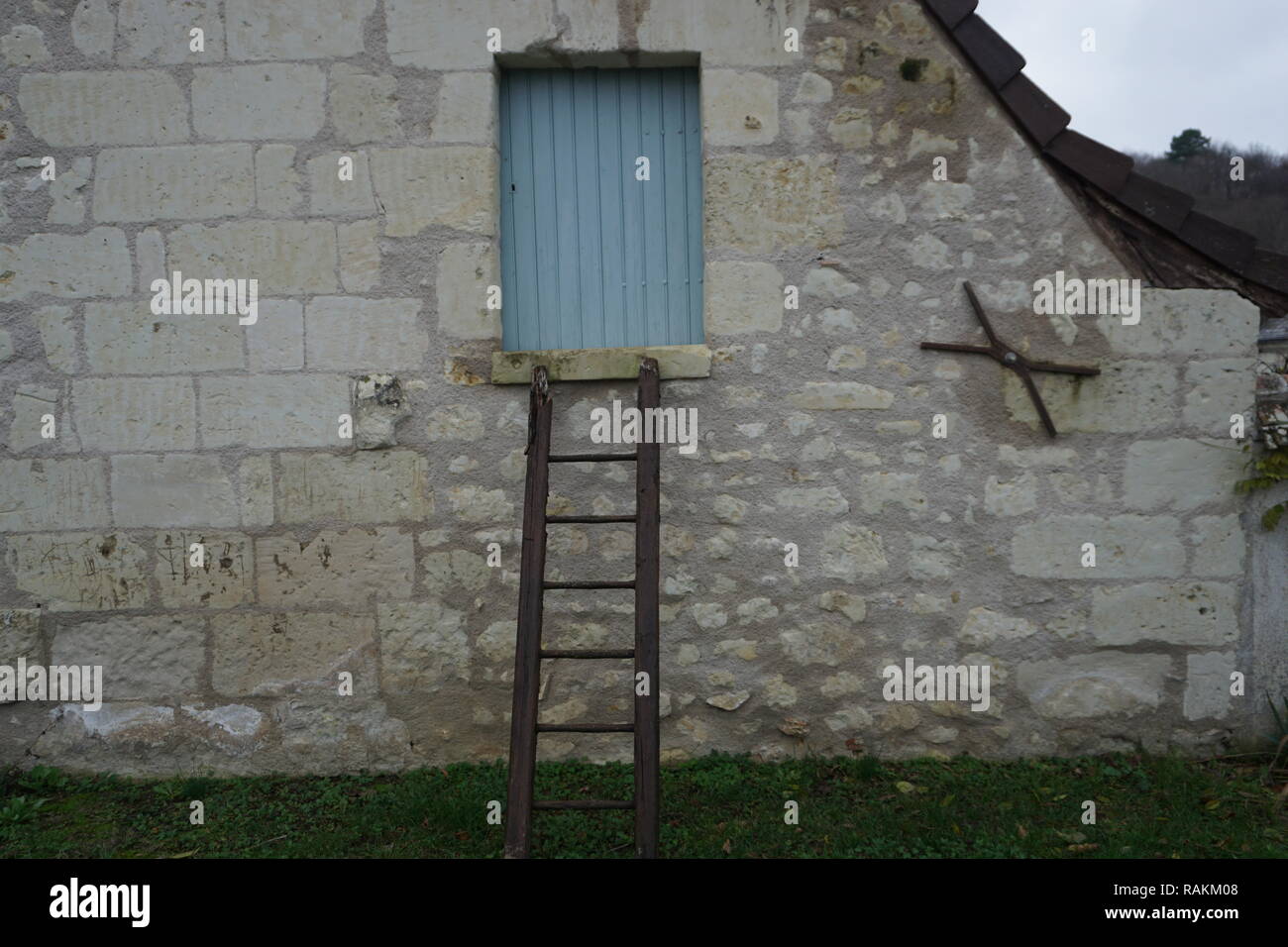 Old fashion wood ladder leaning against the limestone wall of a typical ...
